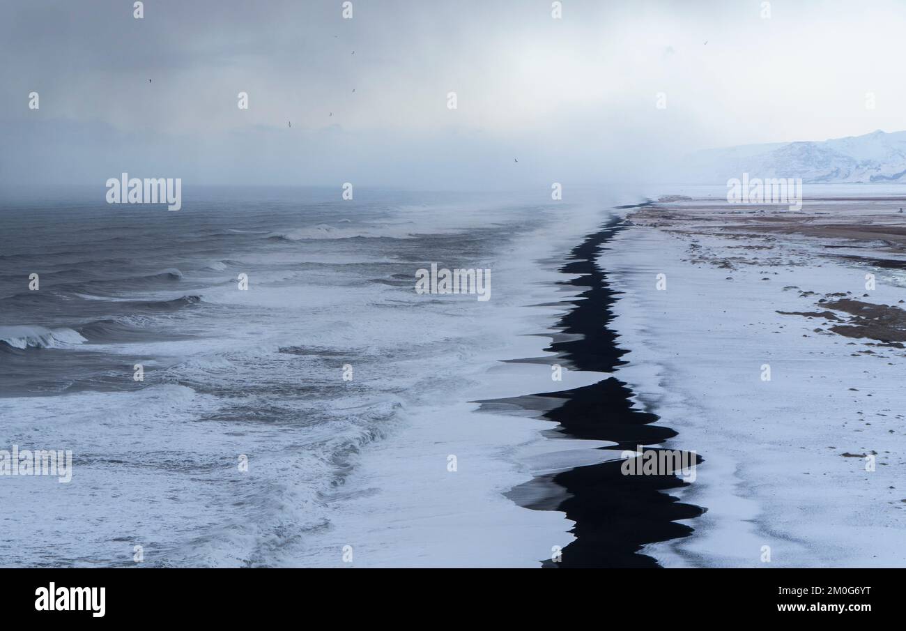 An aerial view of a frozen beach with waves in Dyrholaey, Iceland Stock ...