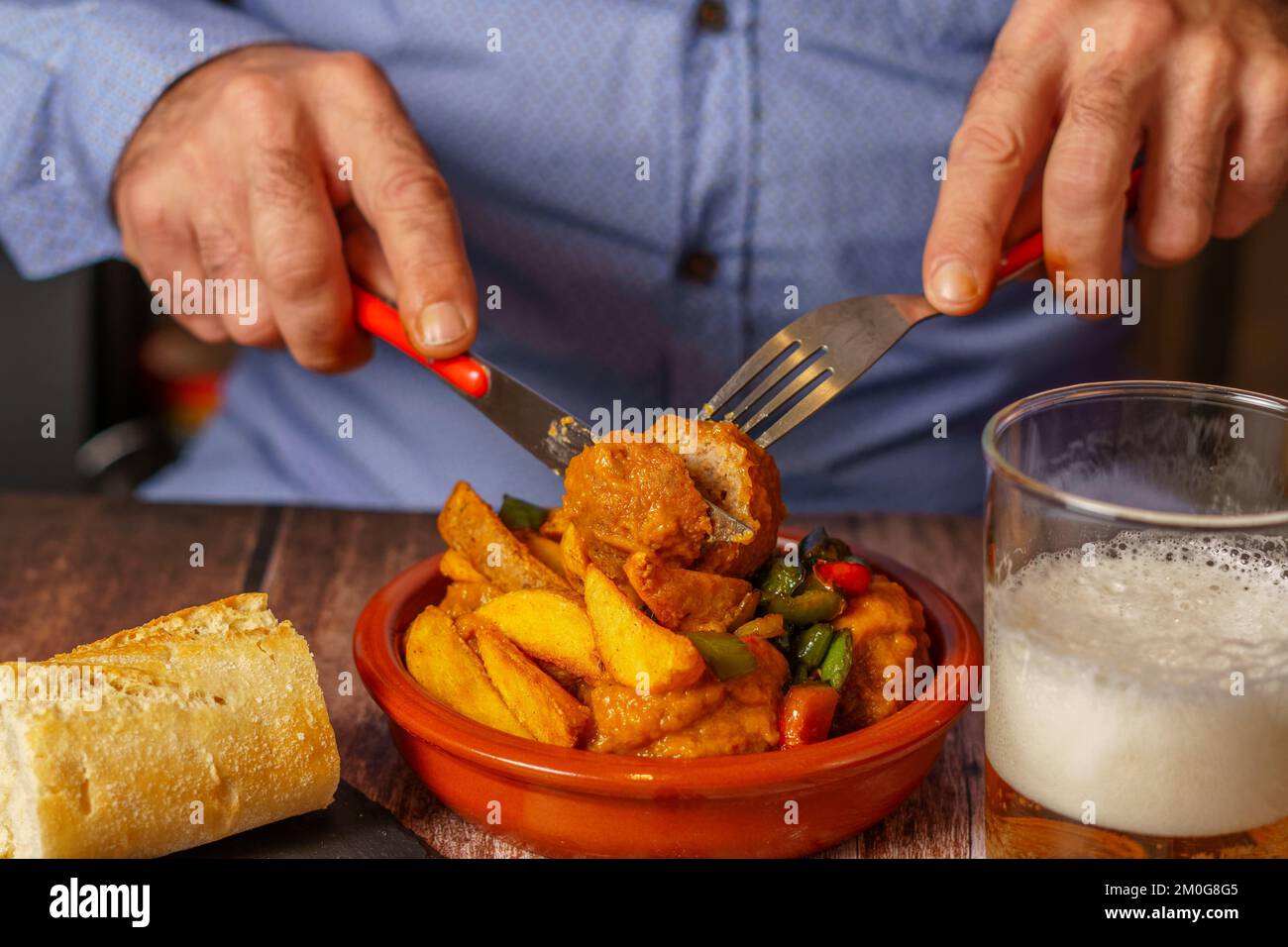 man with blue shirt eating meatballs with spaghetti in a restaurant ...