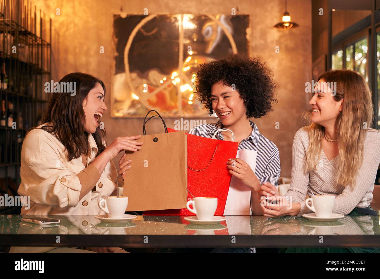 Three friends at the bar cafe giving gifts for Christmas. Friends come ...