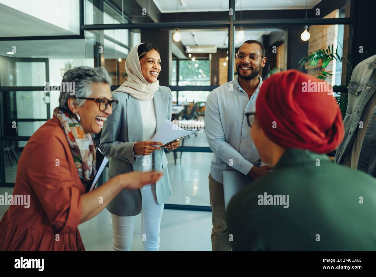 Group of happy business colleagues laughing cheerfully during a staff meeting in a modern office ...