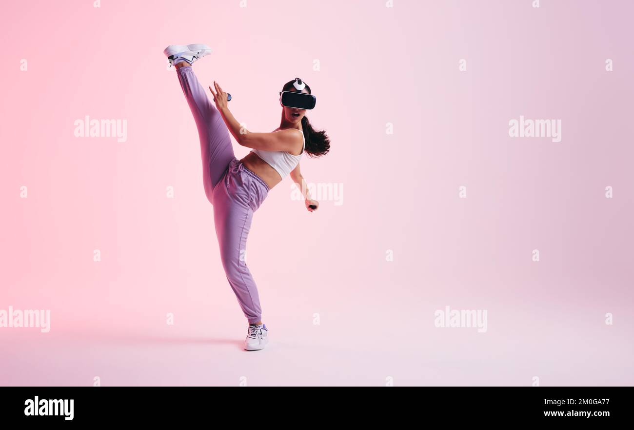 Young woman throwing a kick in an immersive virtual reality game ...