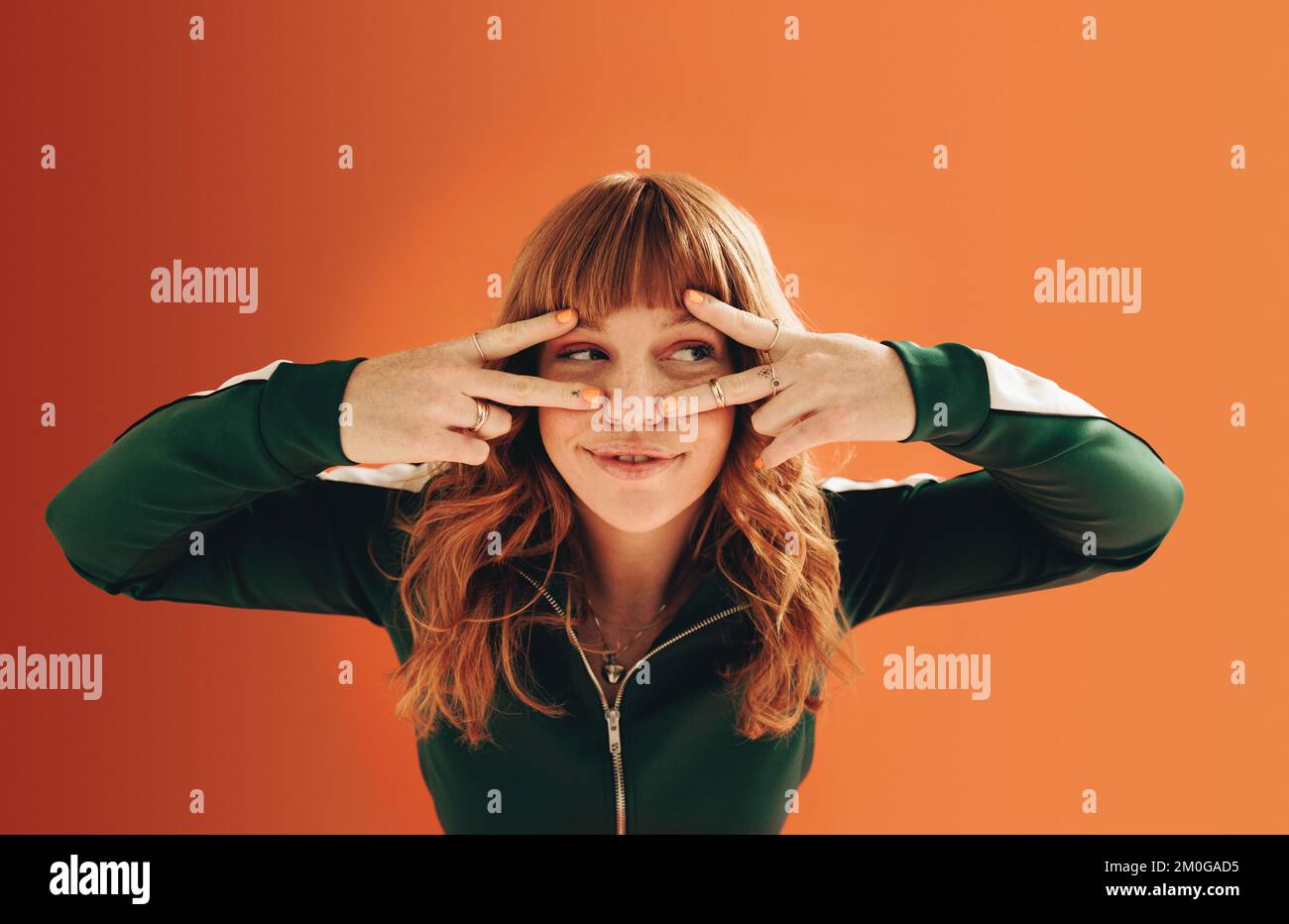 Woman with ginger hair making v signs with her hands. Young woman ...