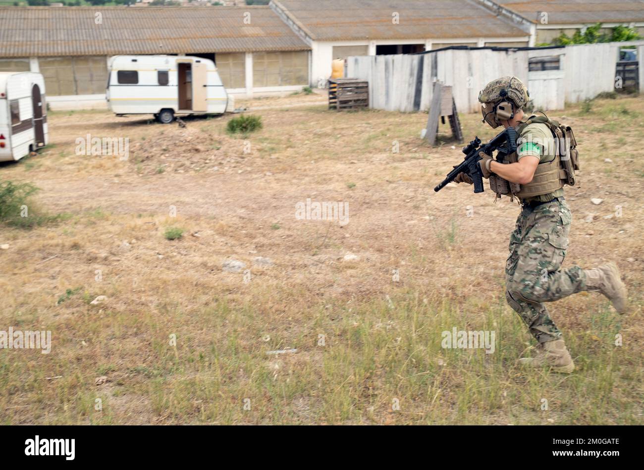 Playfield for the practice of airsoft. Player in full action runs with ...