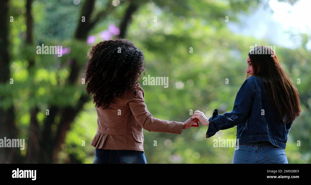 Back of two girlfriends walking together outside in street Stock Photo ...