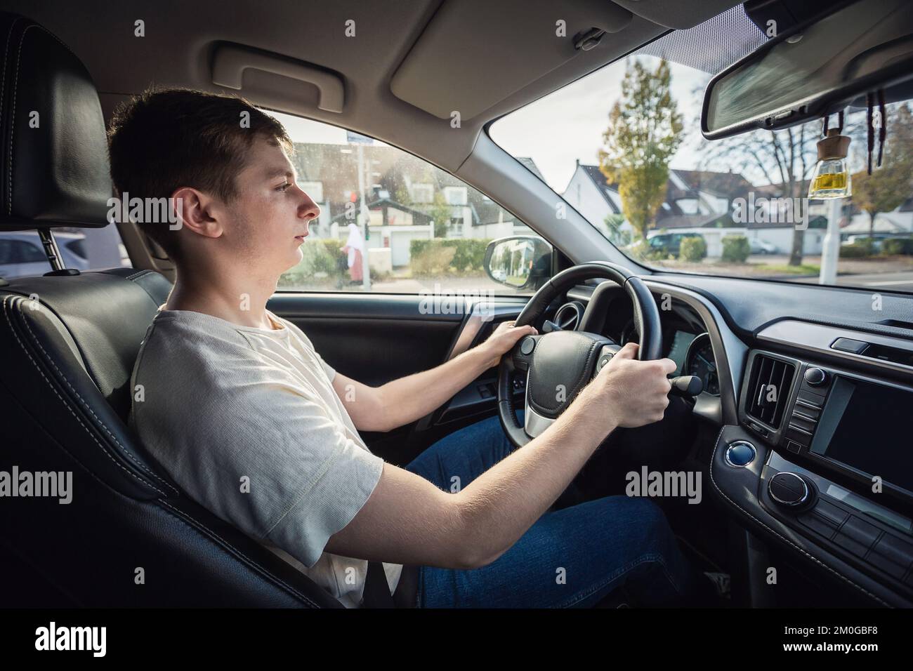 Side view contented young man driving car confident. Teenager driver ...