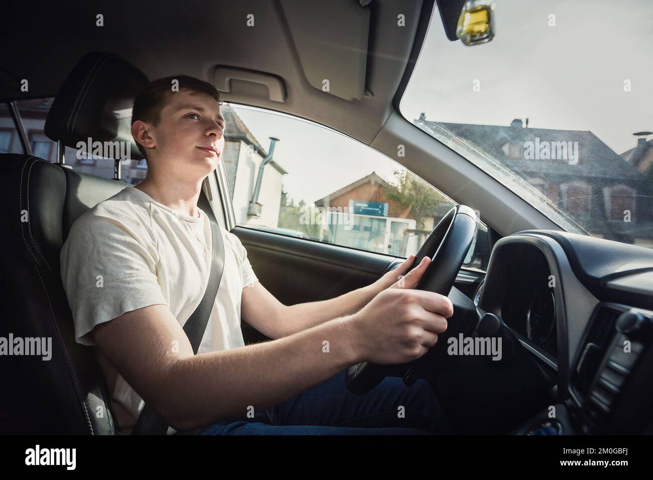 Side view young man driving car confident. Teenager driver enjoying the ...