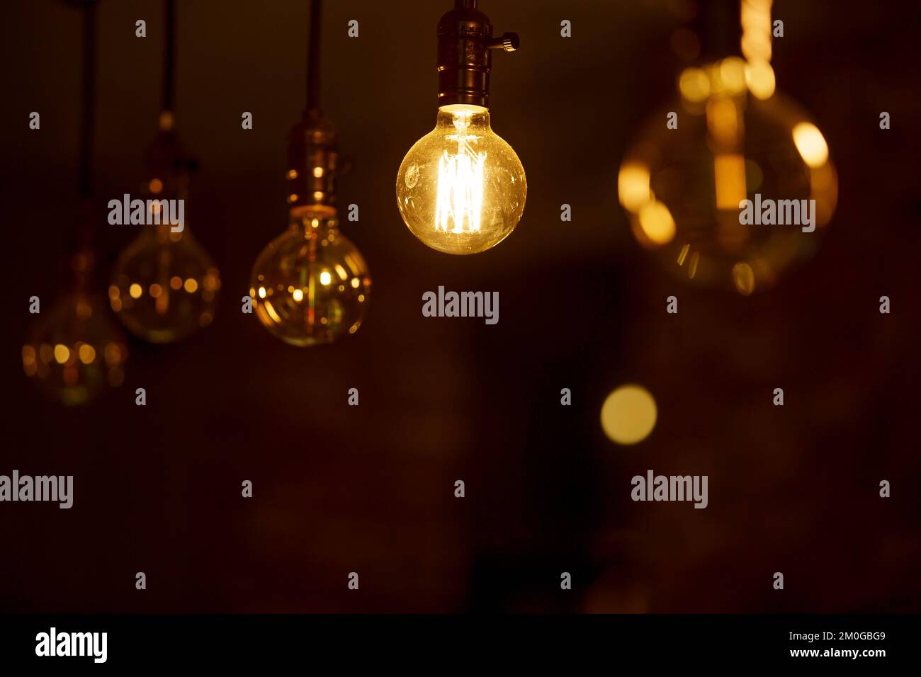 A burning light bulb glows faintly against the background of blurry ...