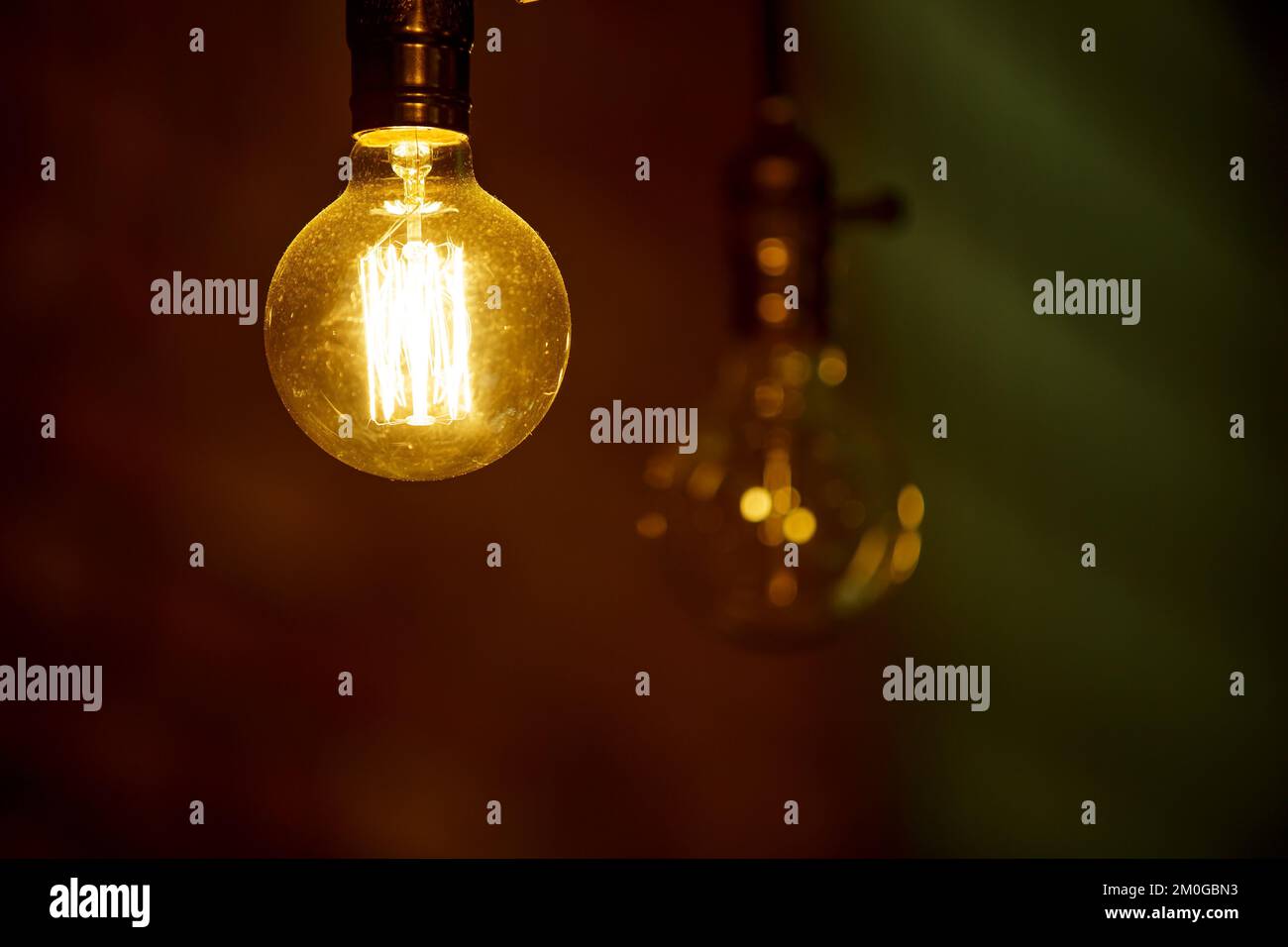 A burning light bulb glows faintly against the background of blurry ...