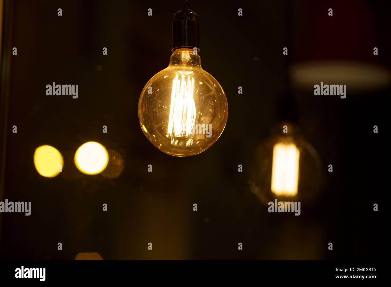 A burning light bulb glows faintly against the background of blurry ...