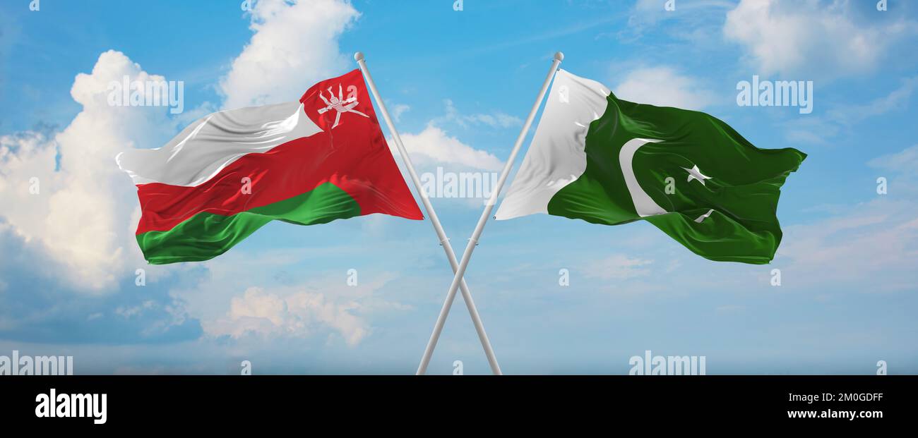 two crossed flags Pakistan and Oman waving in wind at cloudy sky ...
