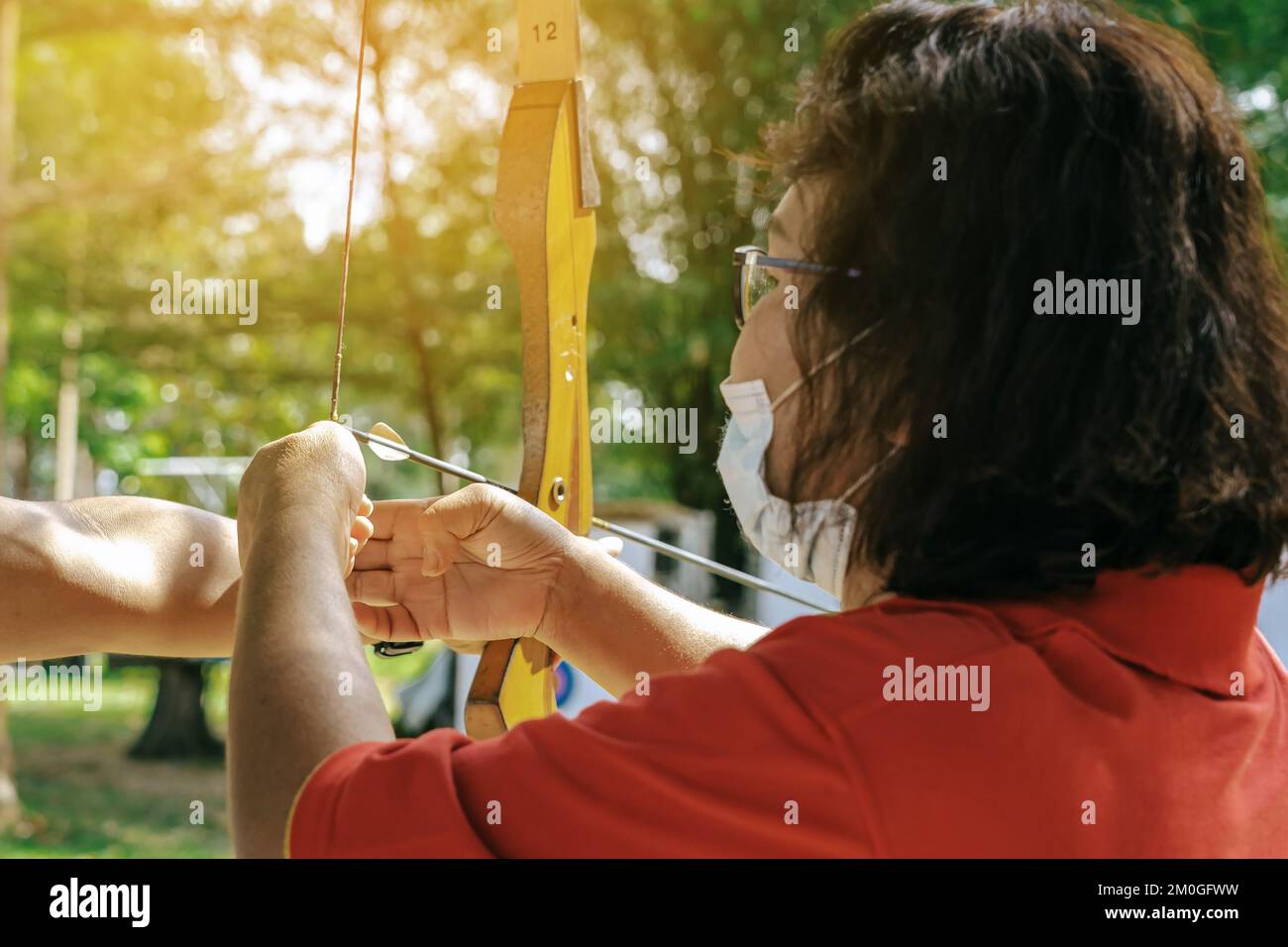 Female teacher teaches student to aim at goal. An archer teaching young ...