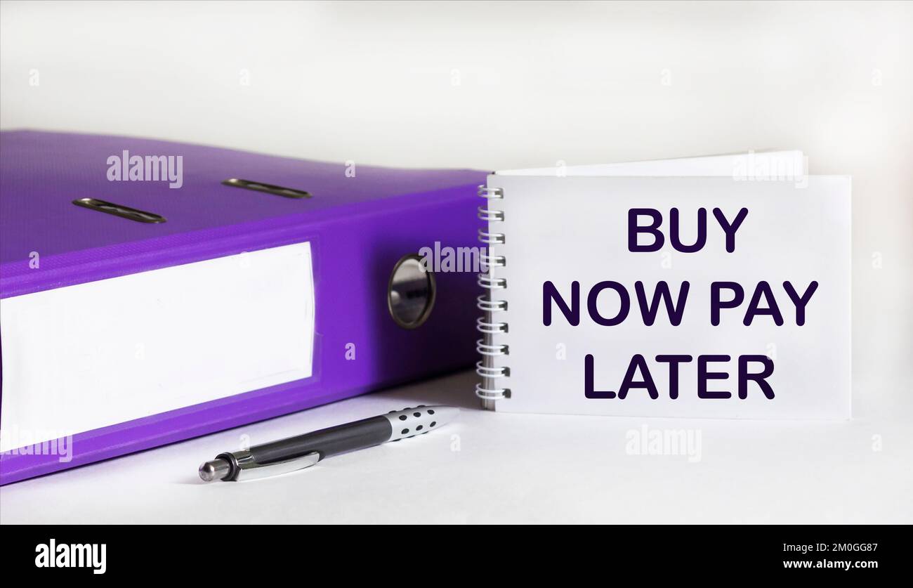 On a white table is a folder with documents, a pen and a notepad with ...