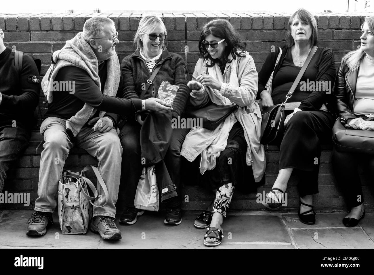 A Man Offers Sweets/Candy To A Woman In The Queue Whilst Waiting To See ...