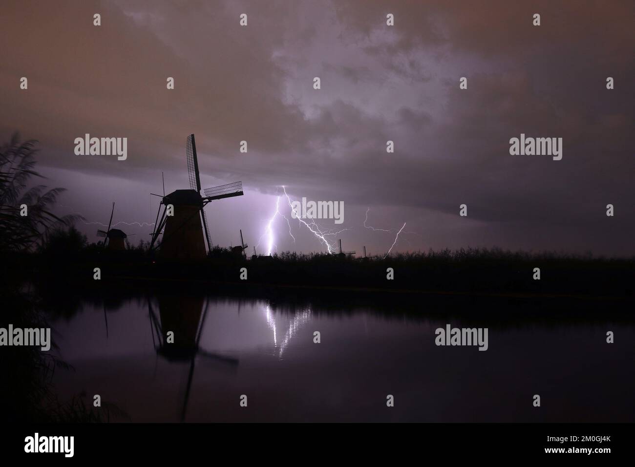 A silhouette of a windmill with a bolt of lightning striking from the ...