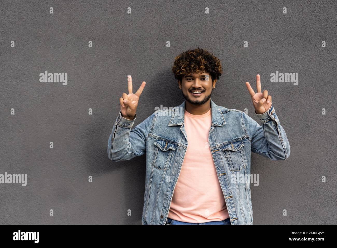 Bearded man showing v sign symbol of peace with fingers, looking at ...