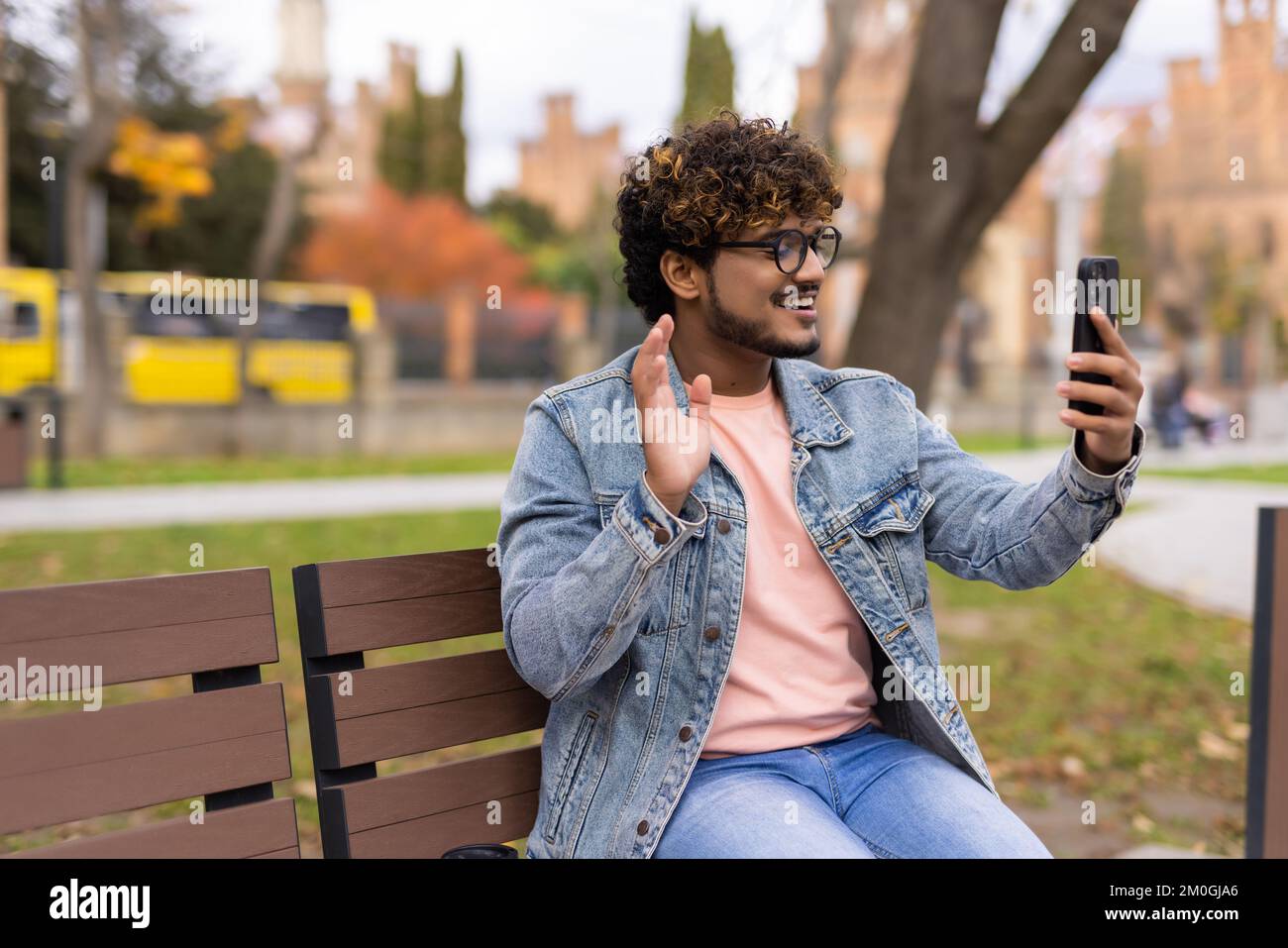 Indian man is talking on video call with his headphones on his phone ...