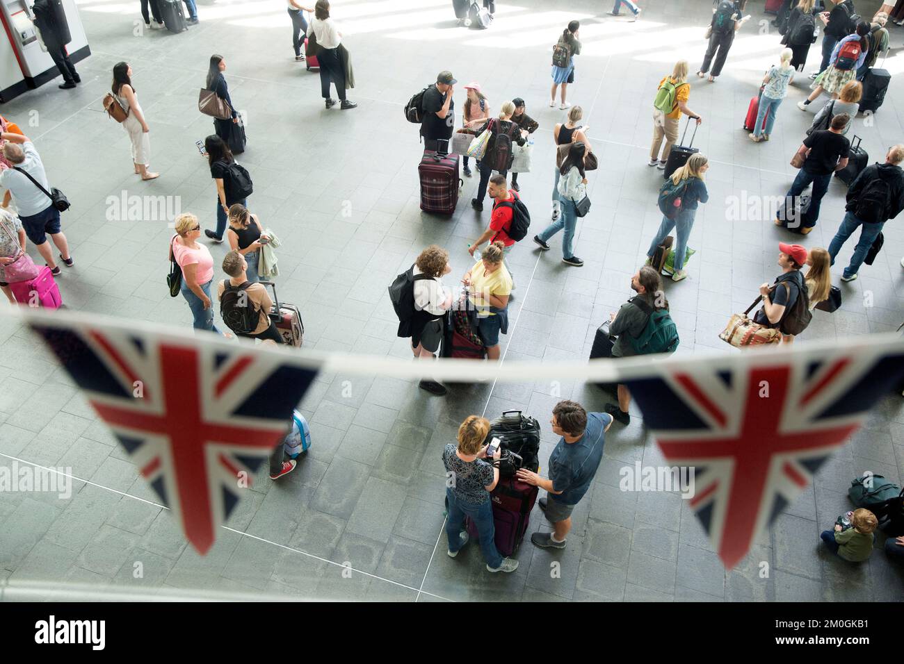 Travellers with suitcases are seen behind a Union Jack bunting at King ...