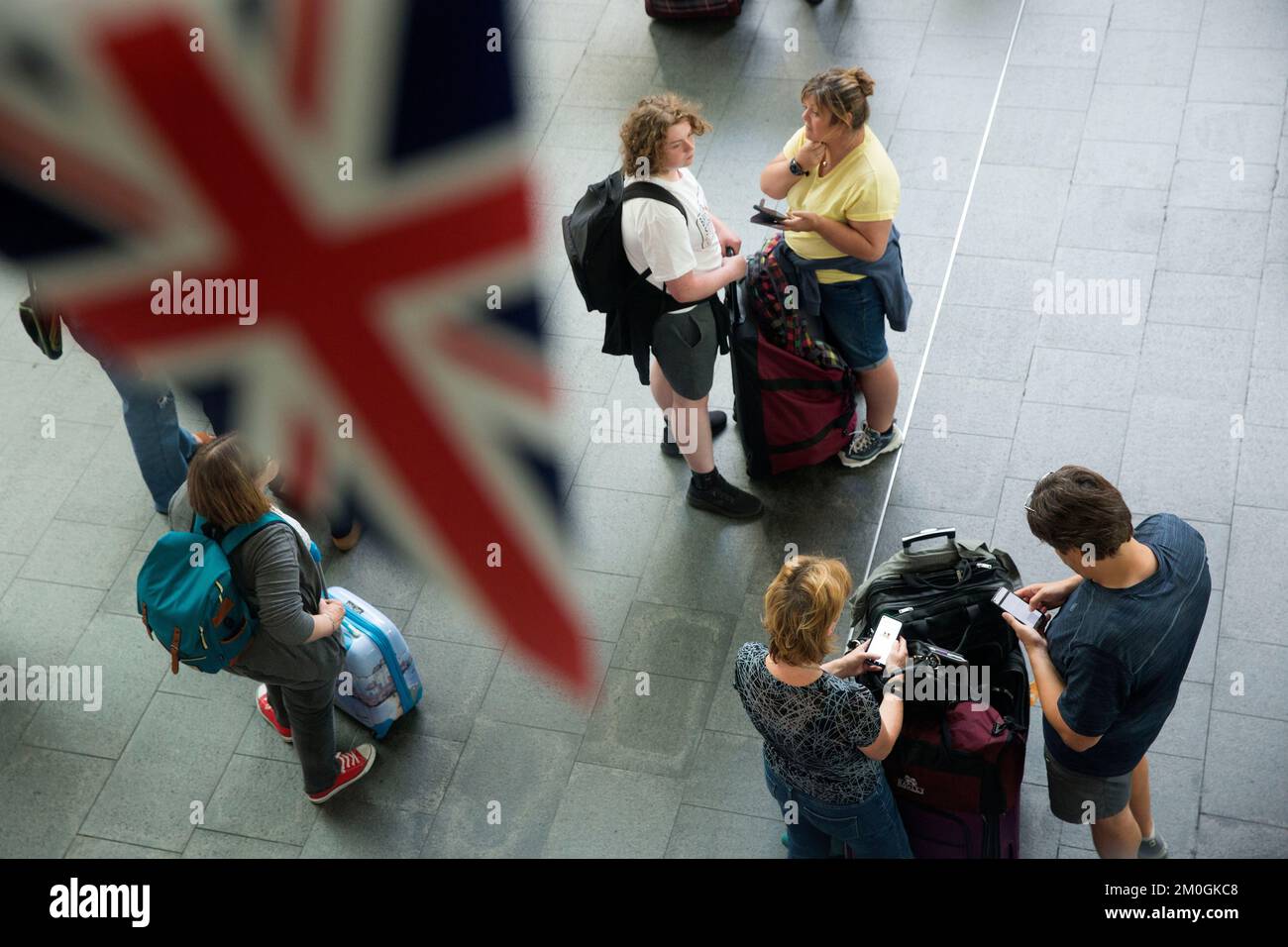 Travellers with suitcases are seen behind a Union Jack bunting at King ...