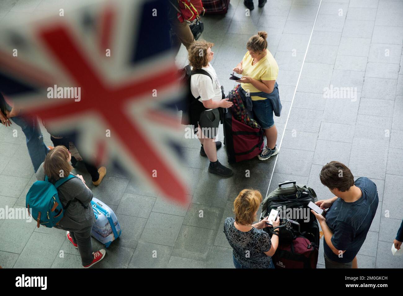 Travellers with suitcases are seen behind a Union Jack bunting at King ...