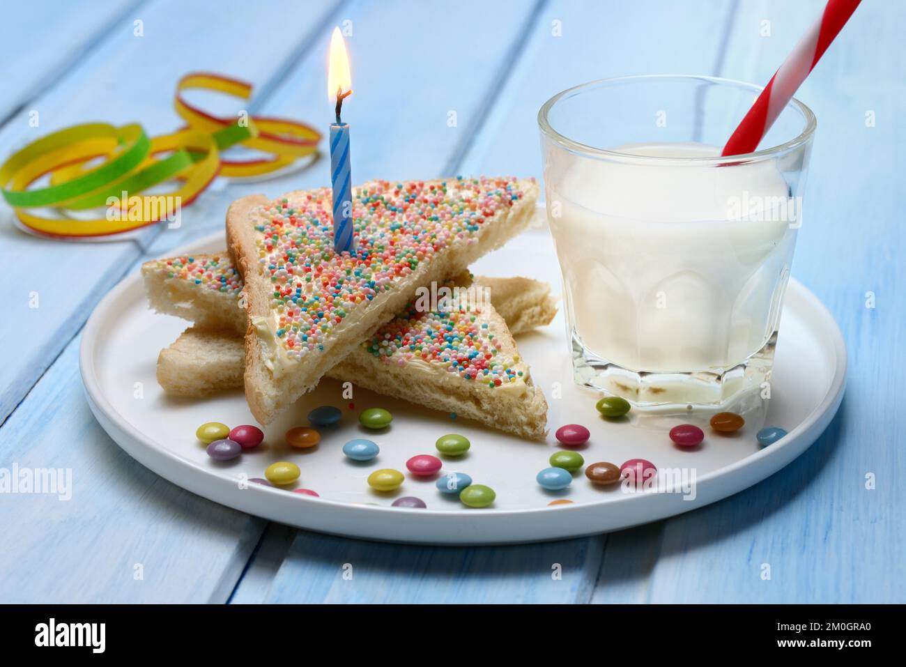 Fairy bread, burning candle on toast with sugar sprinkles and glass of ...