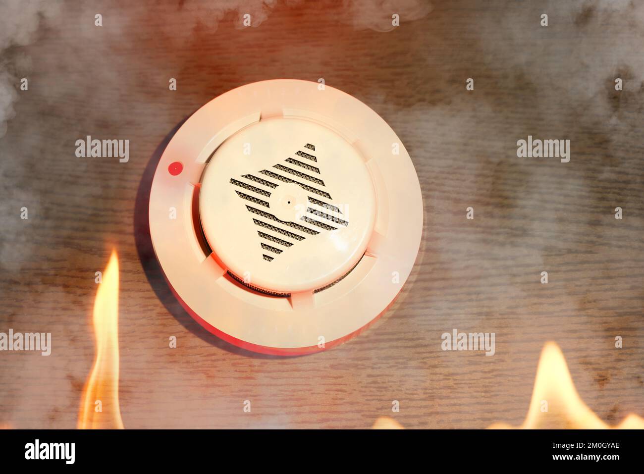 Smoke detector with red alarm indicator during the fire in the building ...