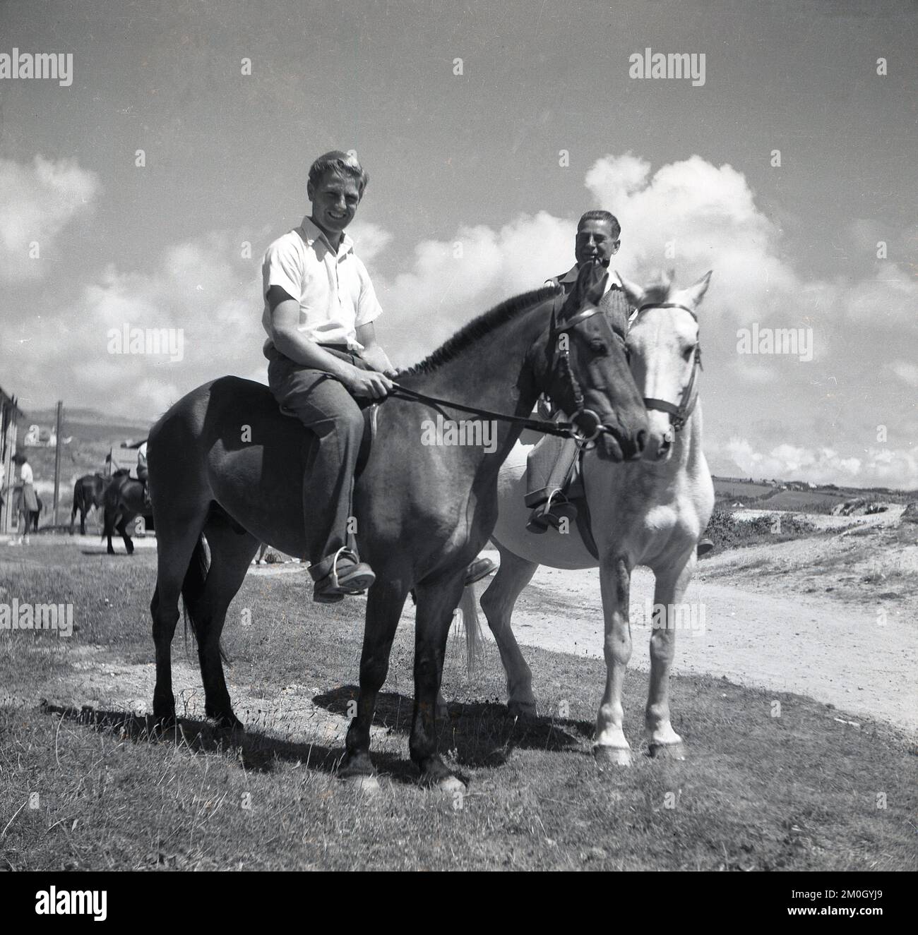 1950s, historical, holiday ride, two men on horses on sandy, grassy ...