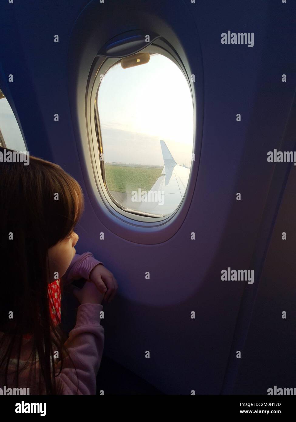 Girl look in airplane window while landing Stock Photo - Alamy