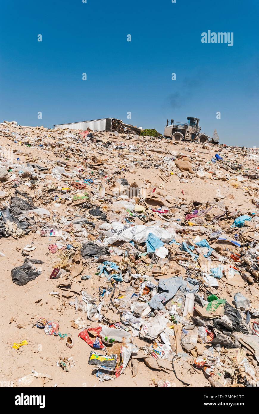A soil compactor, and two trailers dumping trash at an active landfill ...