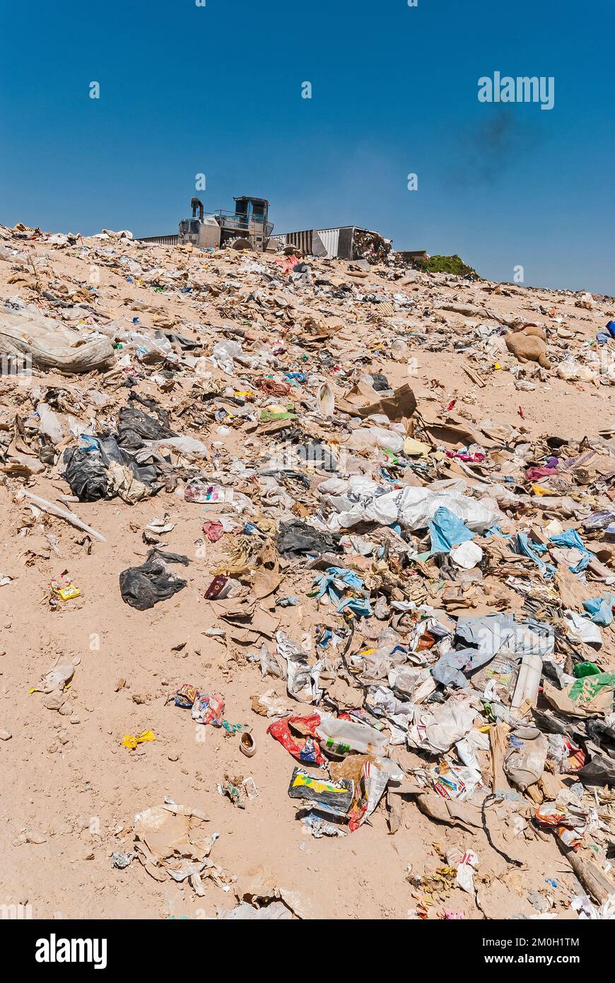 A soil compactor, and two trailers dumping trash at an active landfill ...