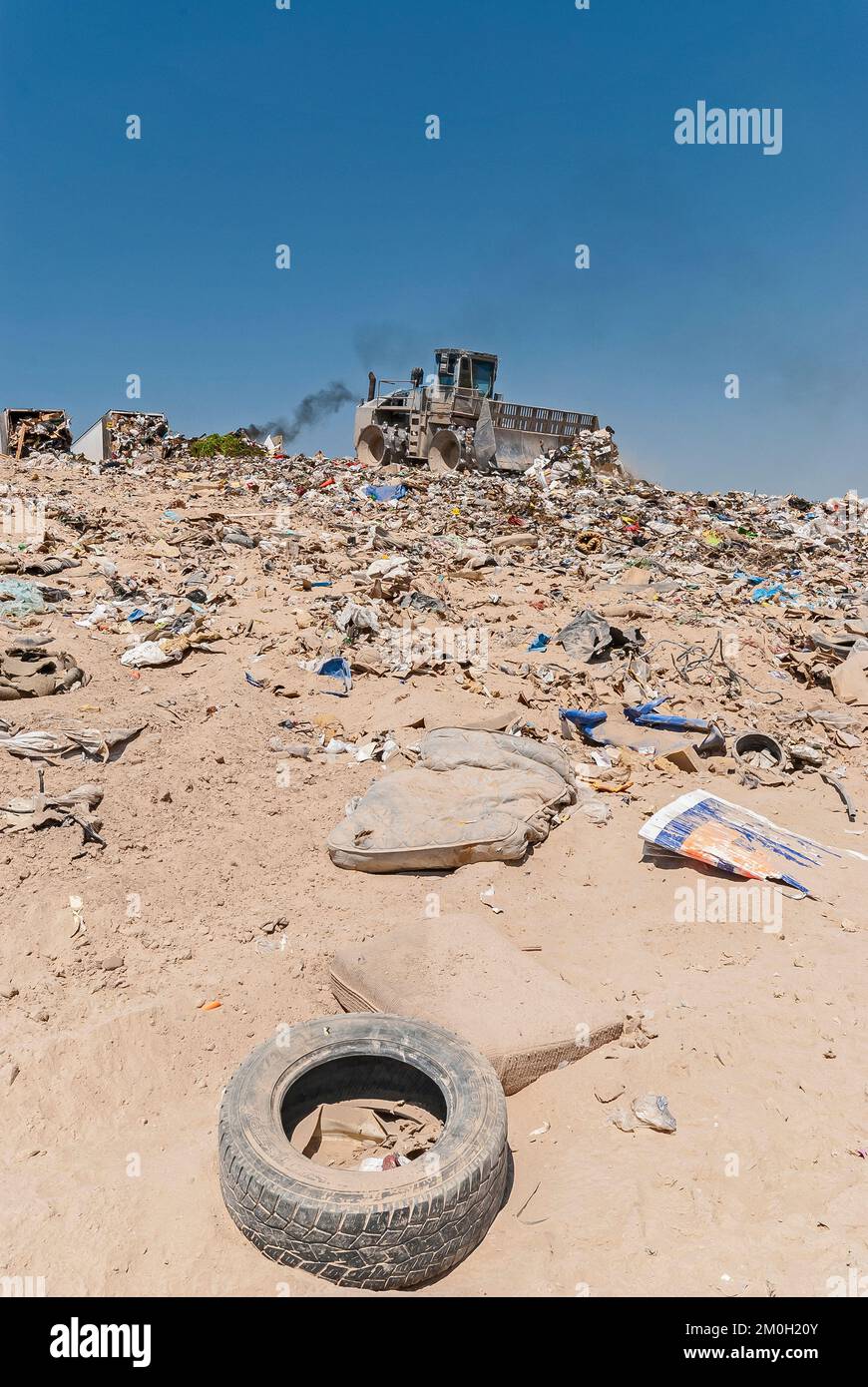 A soil compactor, and two trailers dumping trash at an active landfill ...