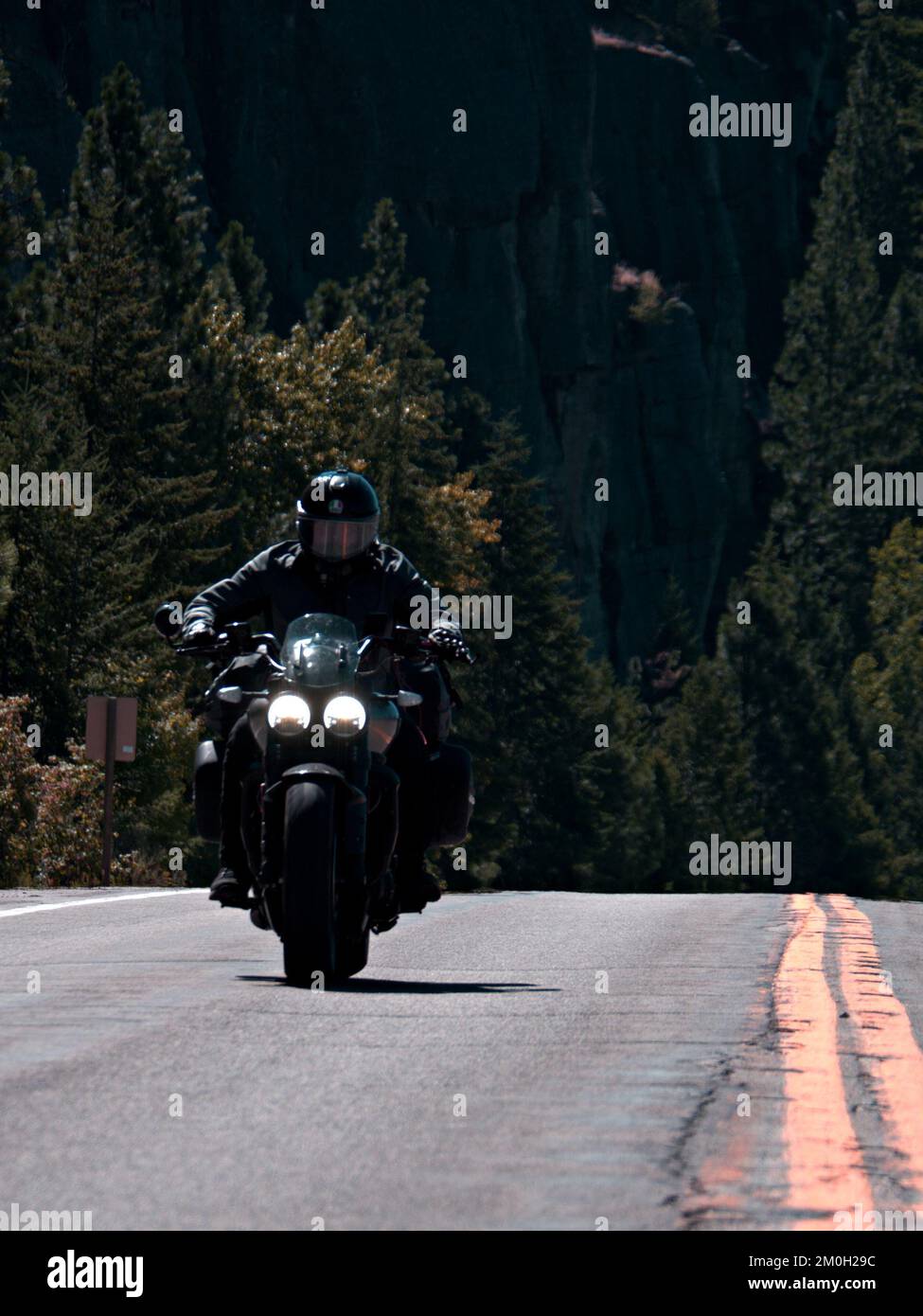 A vertical shot of a biker riding a motorcycle on the highway road near ...