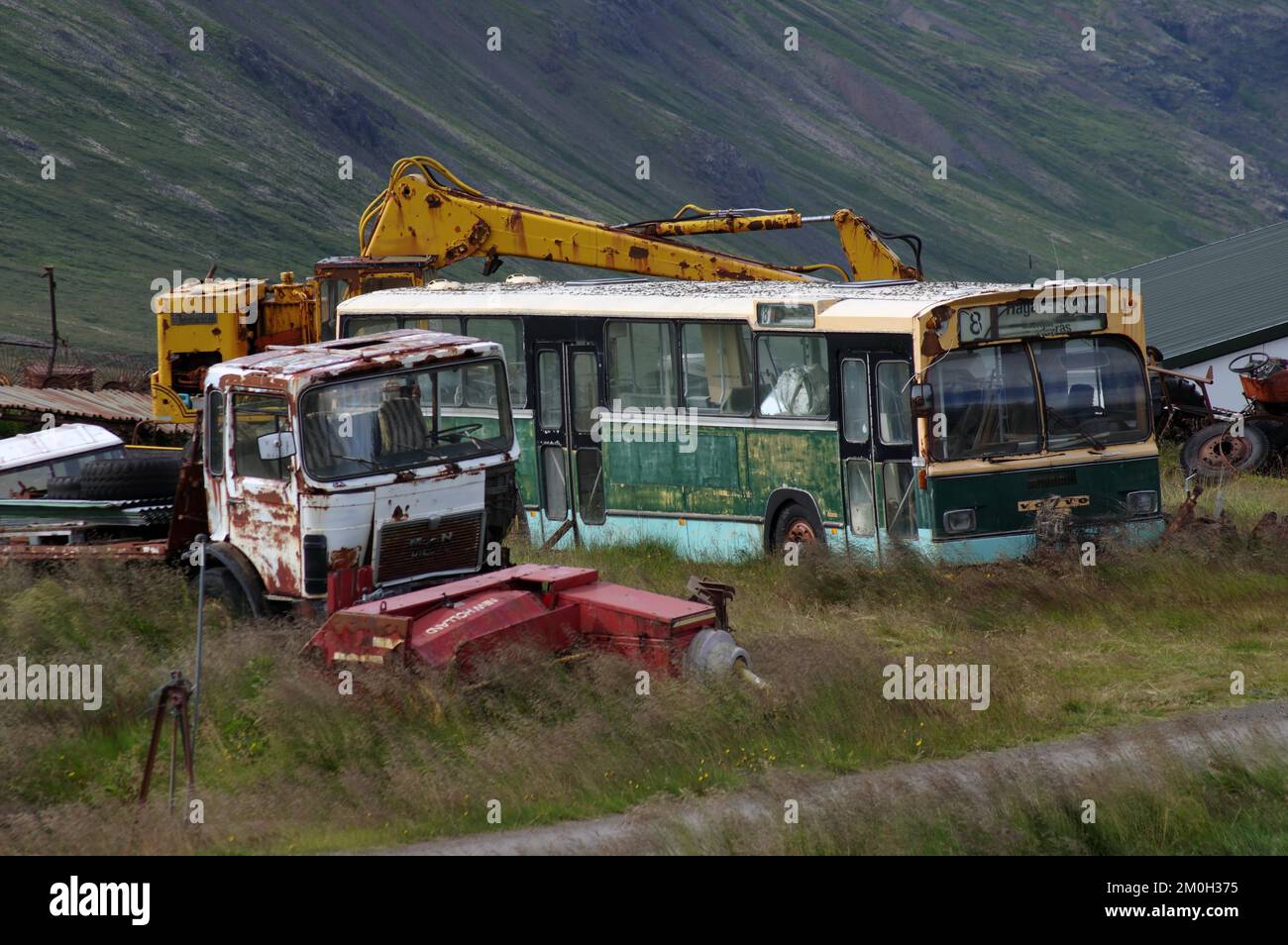 Old buses and construction vehicles standing in a meadow, scrap yard ...