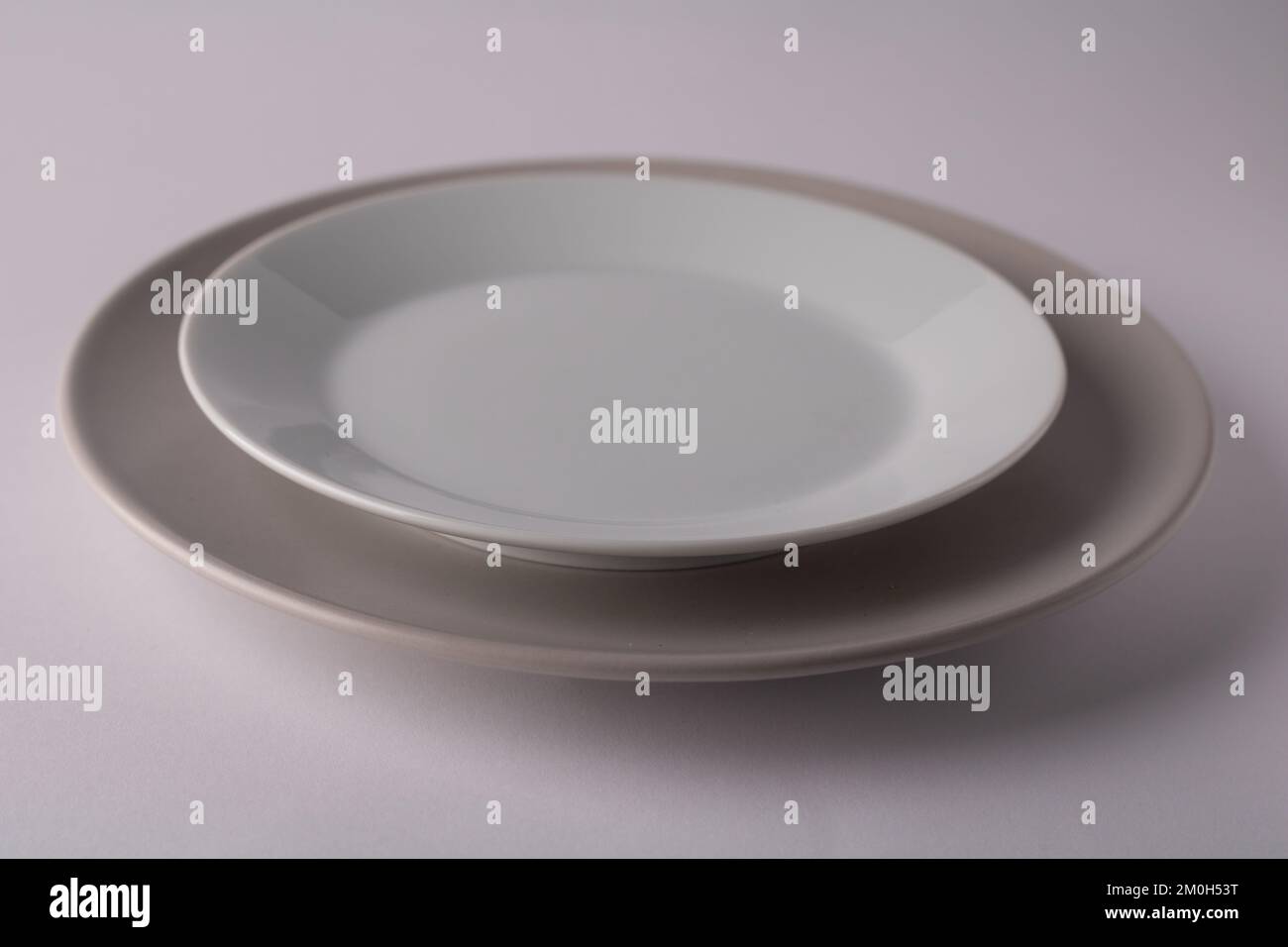 photo of two plates standing on top of each other on a white background ...