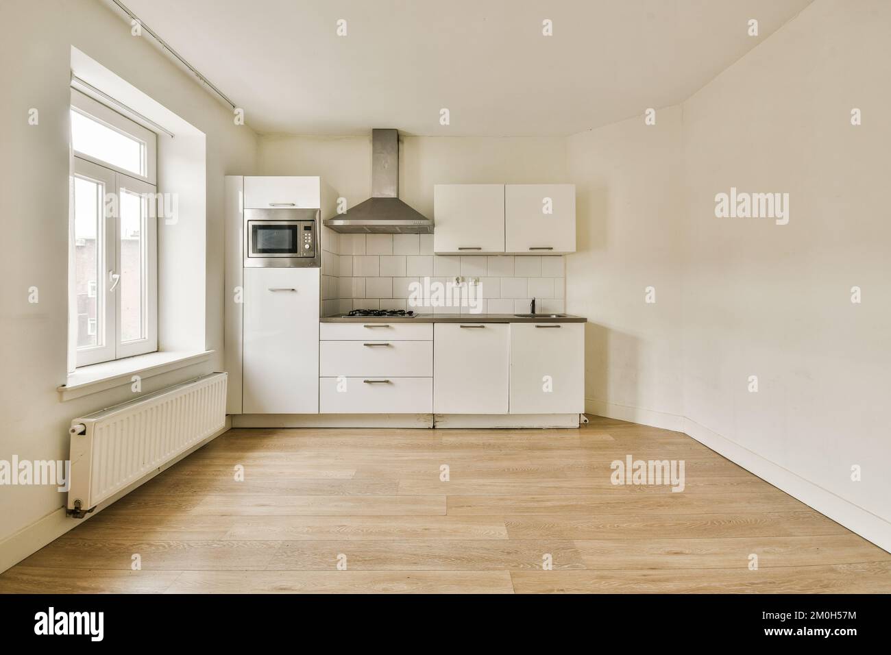 Interior of empty light kitchen with cupboards and appliances located ...