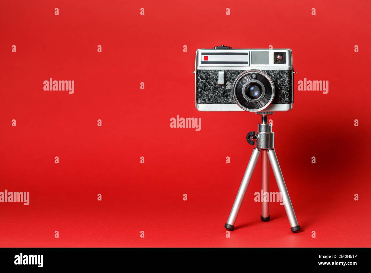 Vintage 60s metal photo camera on aluminium mini tripodon a red ...