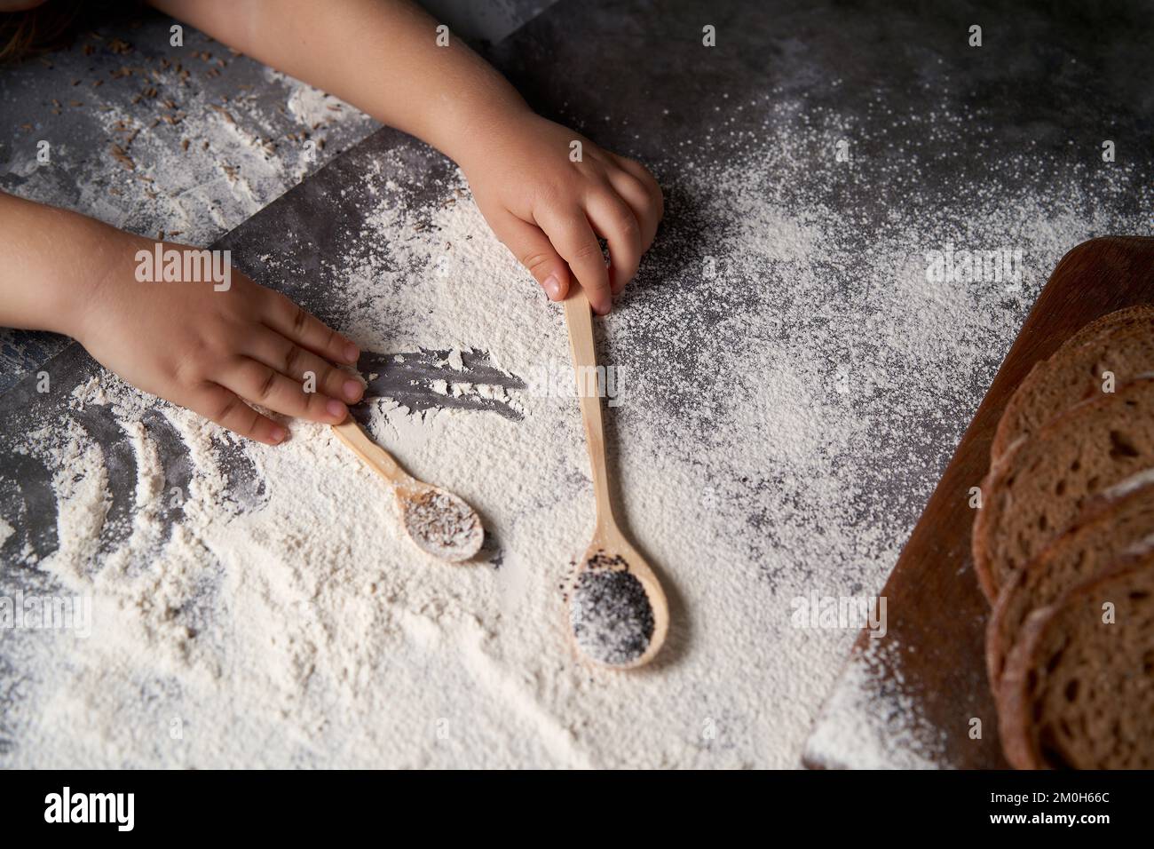 The hands of a kid who helps to make pastries . The child holds wooden ...