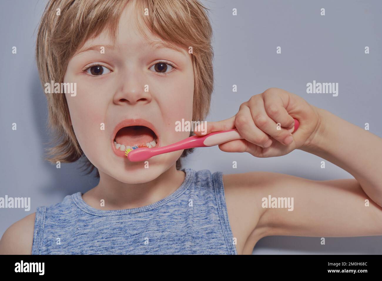 6 year boy on gray brushing teeth Stock Photo - Alamy