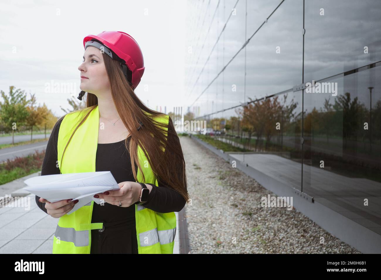 Surveyor in a green work uniform and pink helmet with a map Stock Photo ...