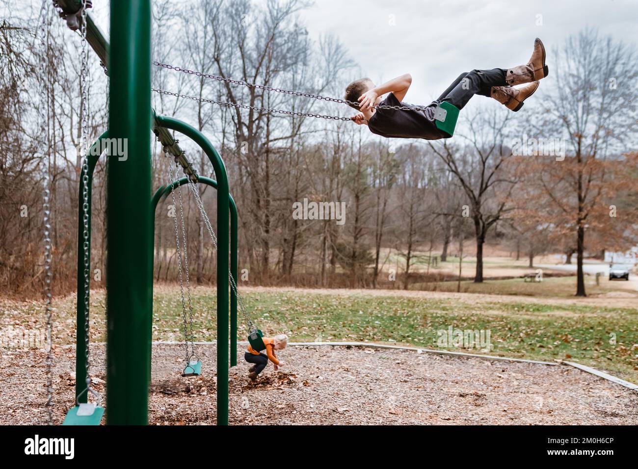 Kids swinging on swing set at park in fall Stock Photo - Alamy
