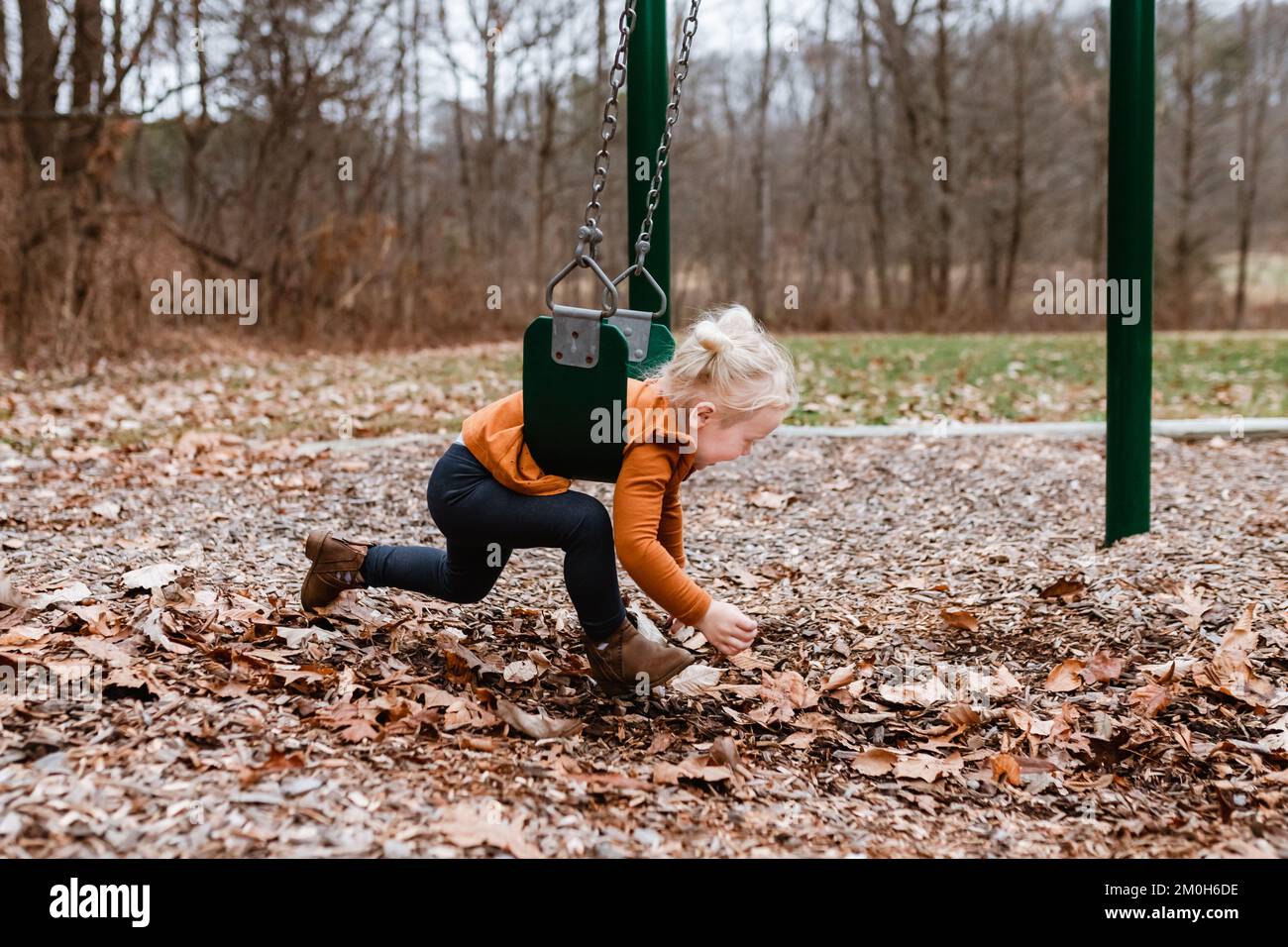 Happy child on swing playing at playground Stock Photo - Alamy