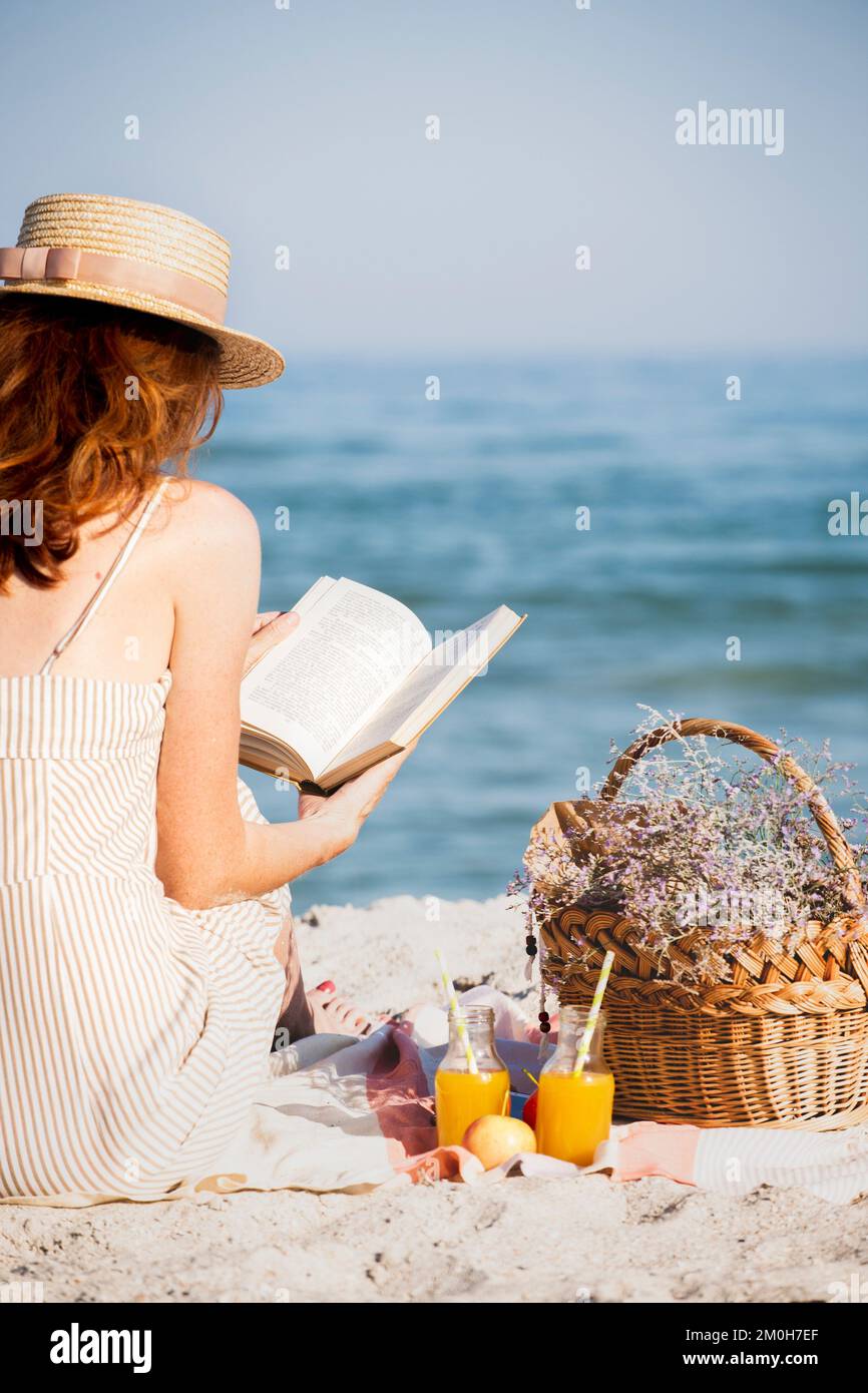 Summer - picnic by the sea. Girl in Hat and basket for a picnic with ...