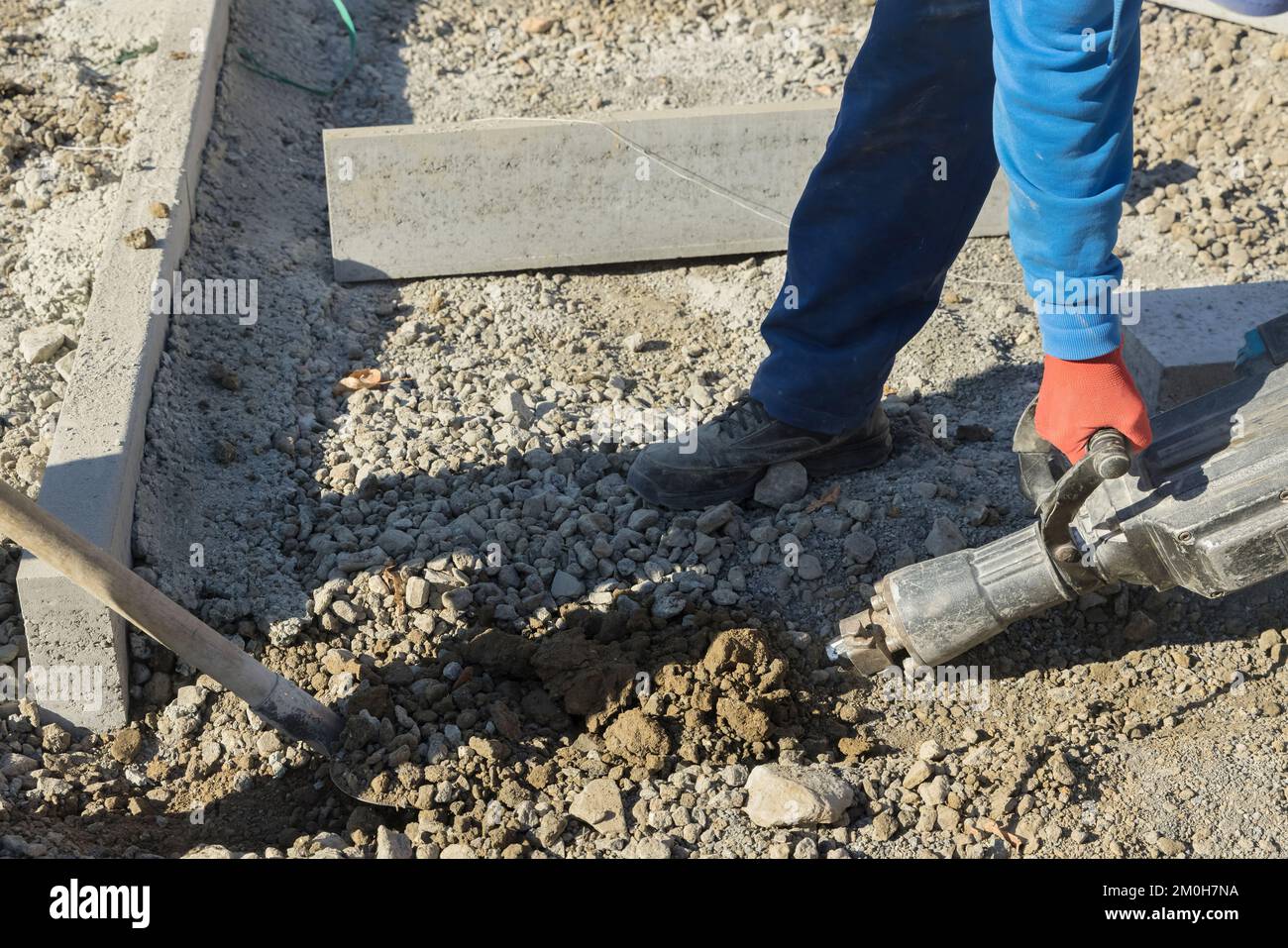 Working on construction road, workers use jackhammer to drill into and ...