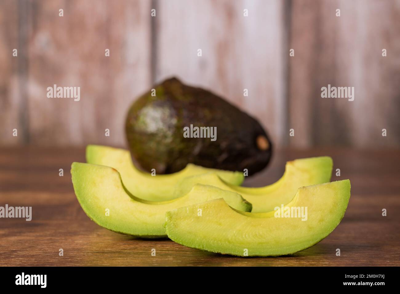 Avocado chunks on a rustic wooden table, with an avocado in the ...