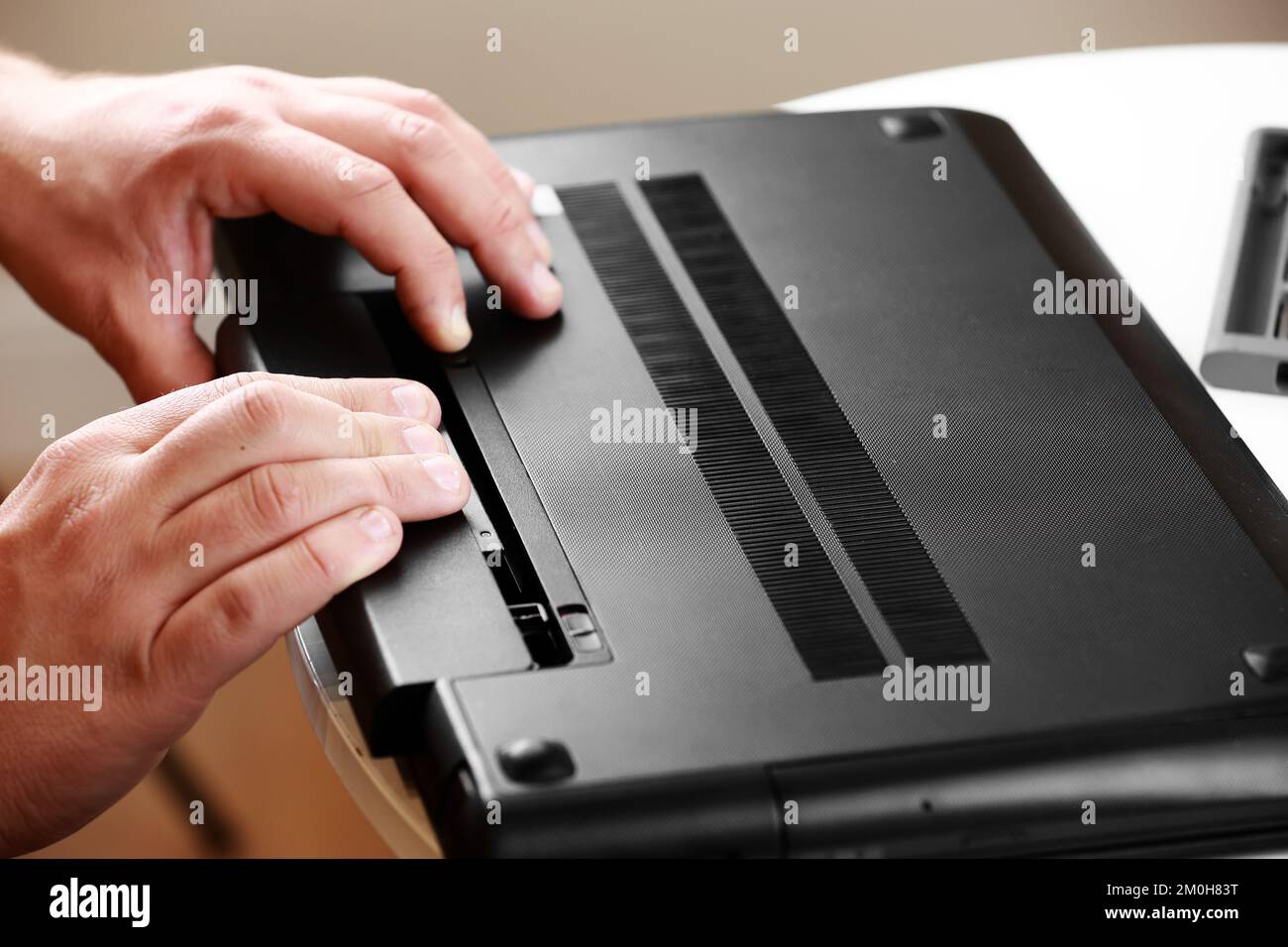 Repairman's hands removing the power battery from the laptop. Computer service and repair ...