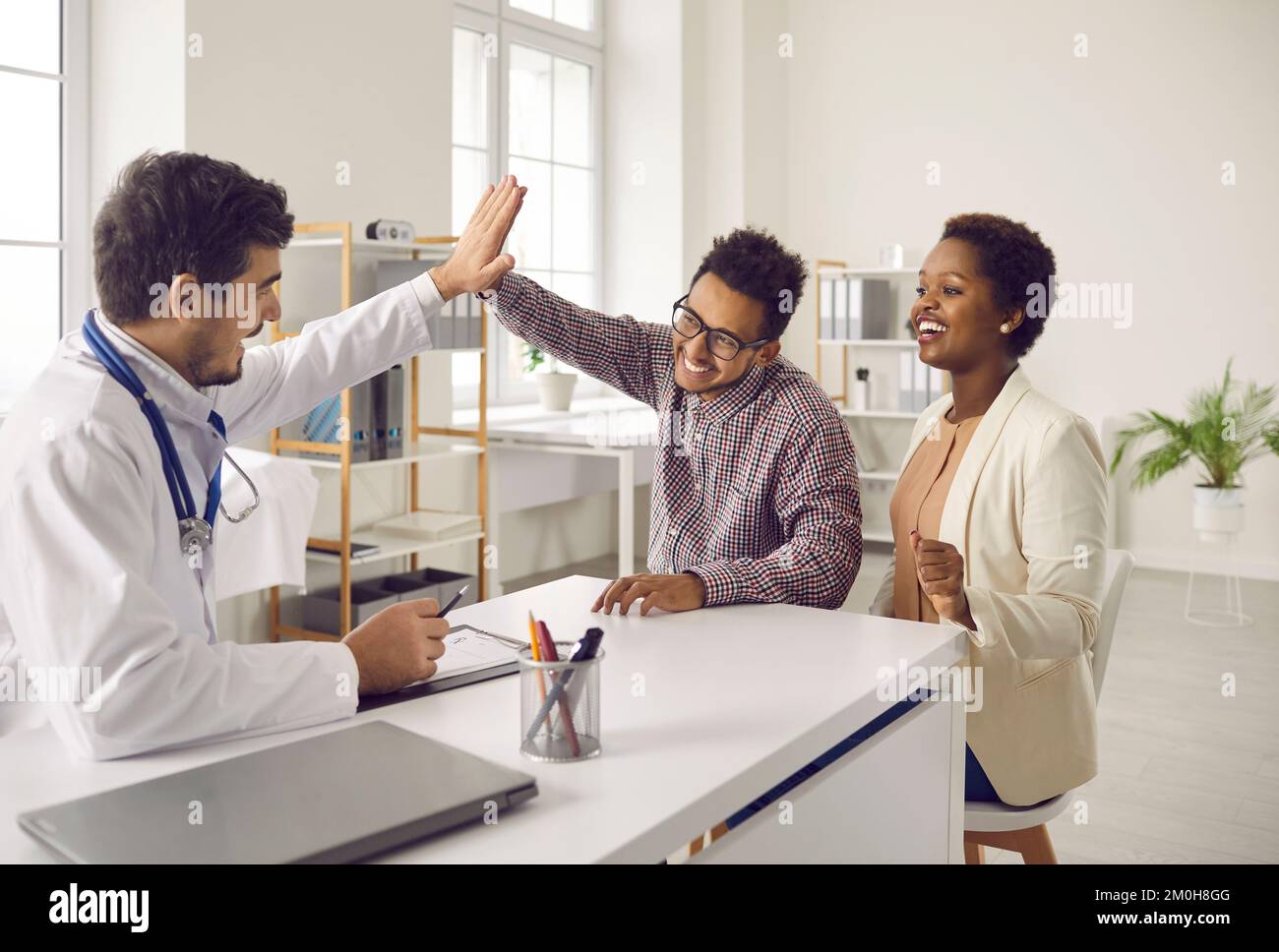 Happy male doctor give high five to excited coupe patients Stock Photo ...