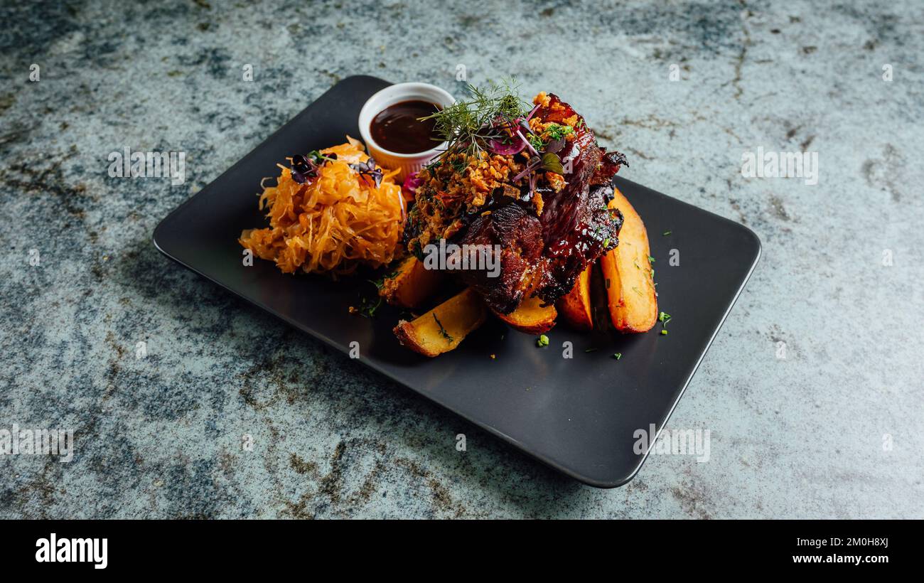 A closeup shot of beef meat with fried potatoes served in the black ...