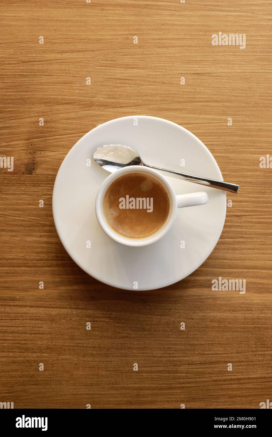 Top view of white porcelain cup with plate and metal spoon of hot ...