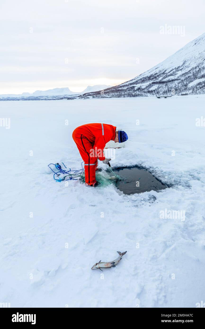 Sweden, Norbotten County, Sami fisherman using the traditional ice hole ...