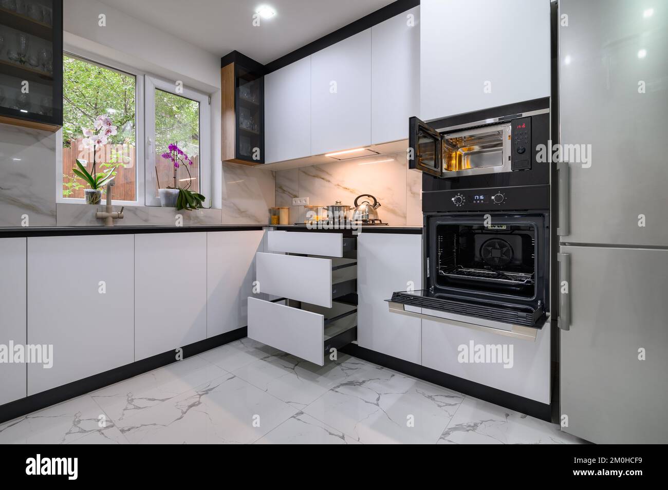 A beautiful kitchen with a white and marble design, a marble floor, an ...
