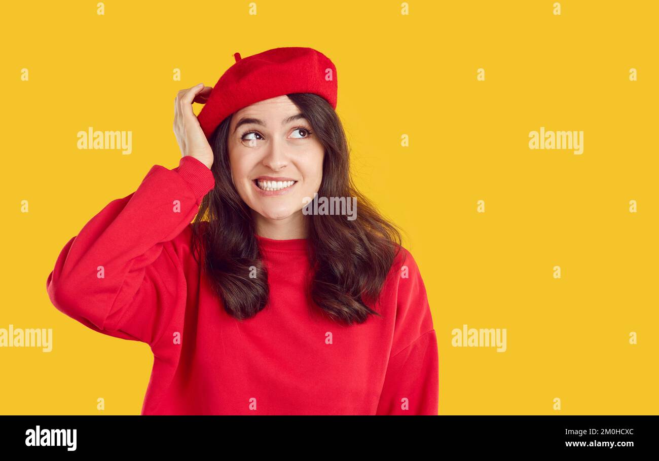 Confused smiling brunette woman in red beret and sweatshirt looking ...